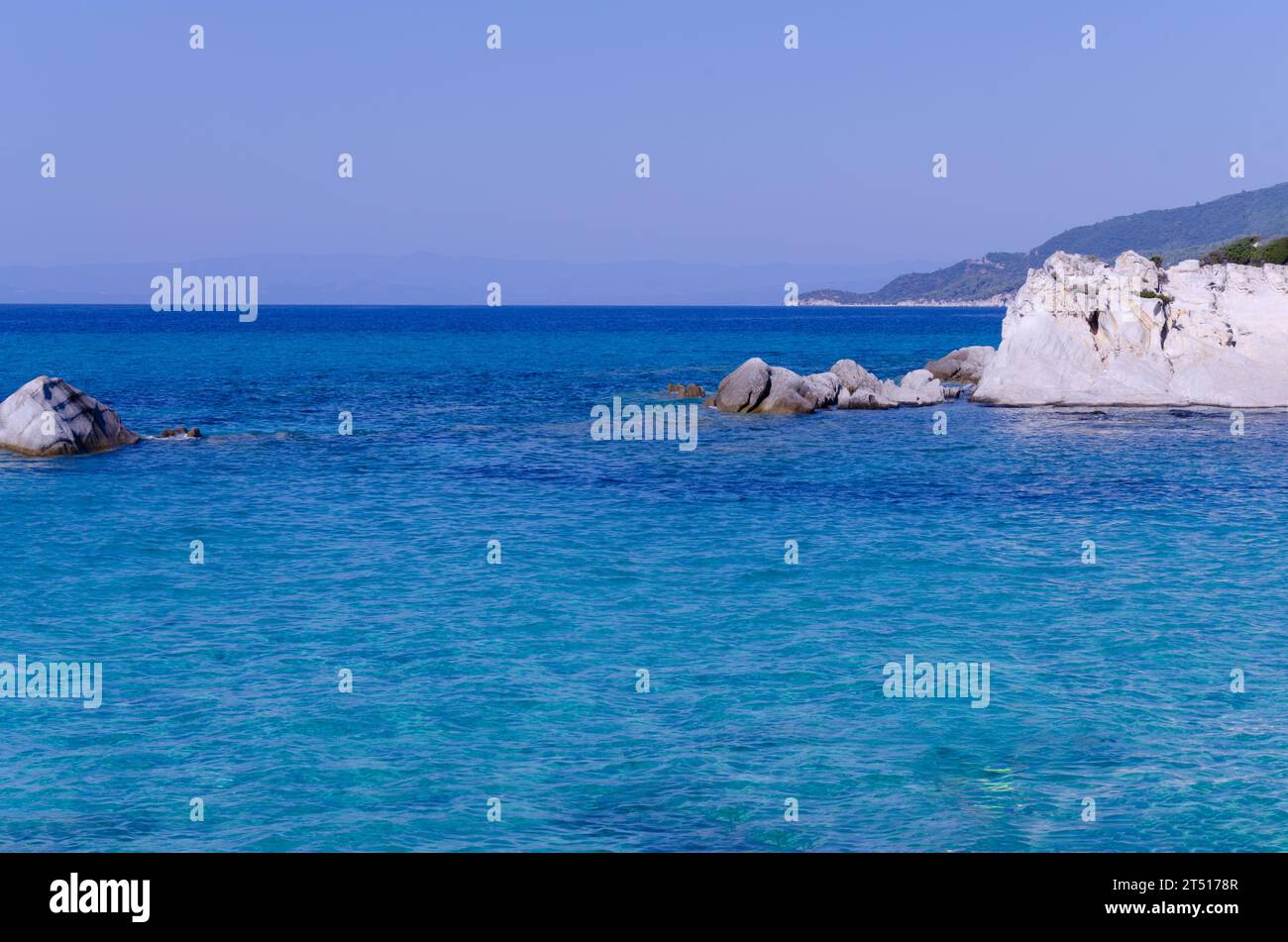 Wedge of white rocky shore in blue sea, horizon line, sky. Background ...
