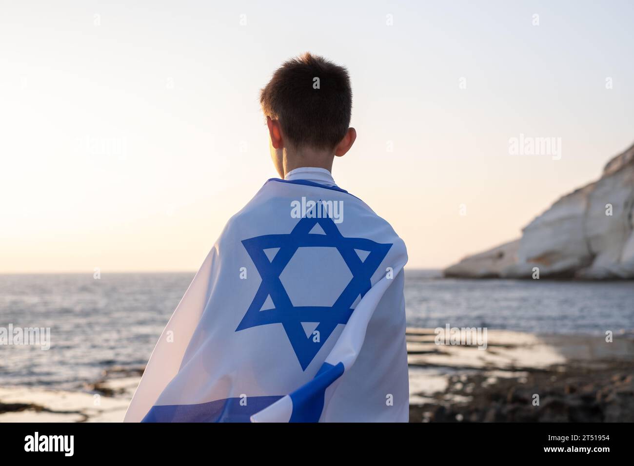 An Israeli teenager boy stands proudly wrapped in the flag of Israel ...