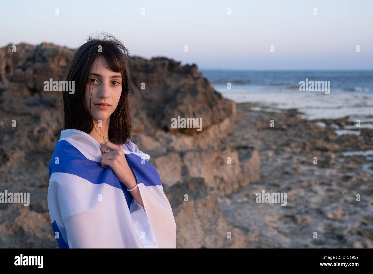 An Israeli teenager girls stands proudly wrapped in the flag of Israel ...