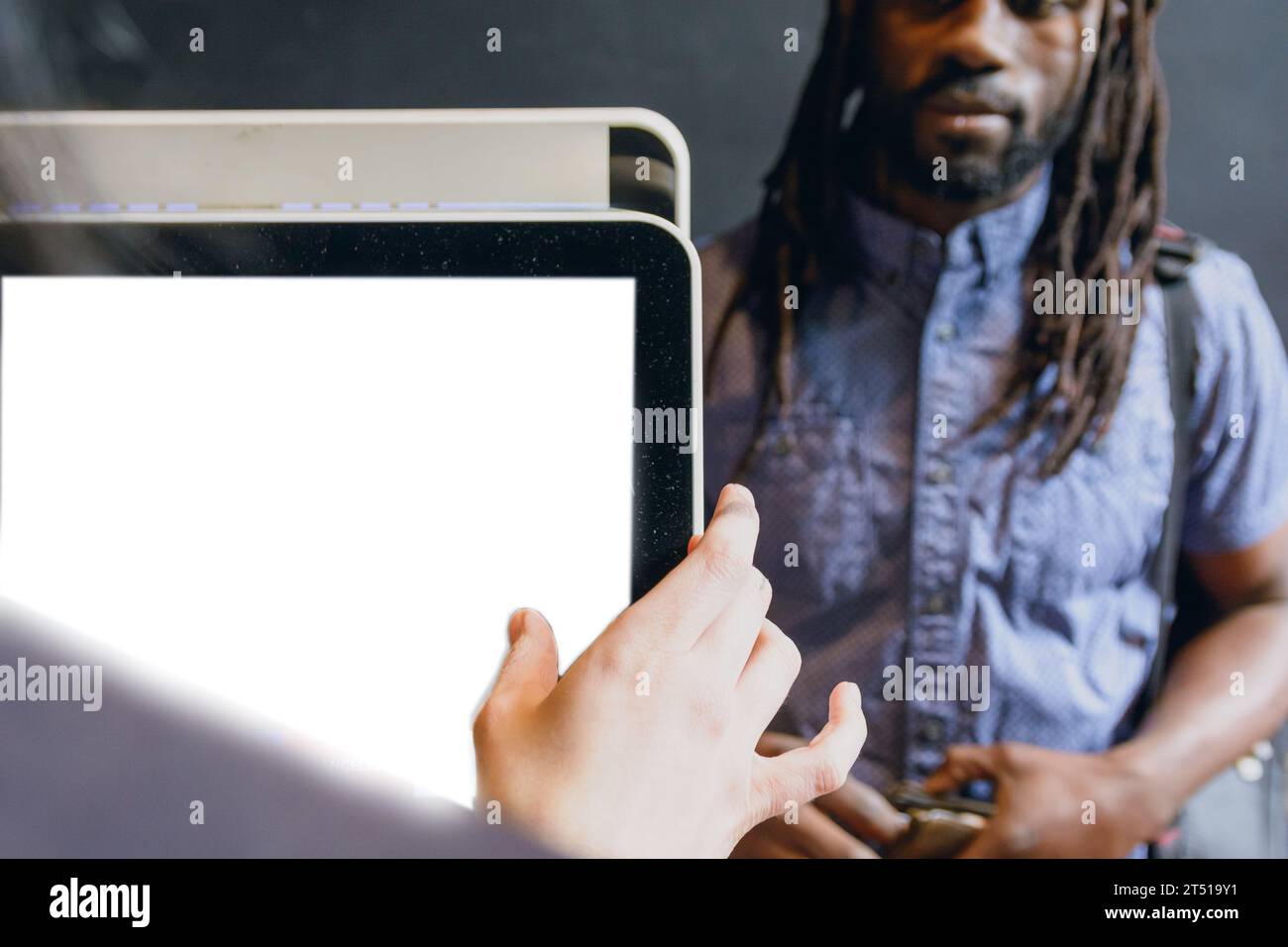 Unrecognizable woman's hand with finger touching computer touch screen taking order from ...