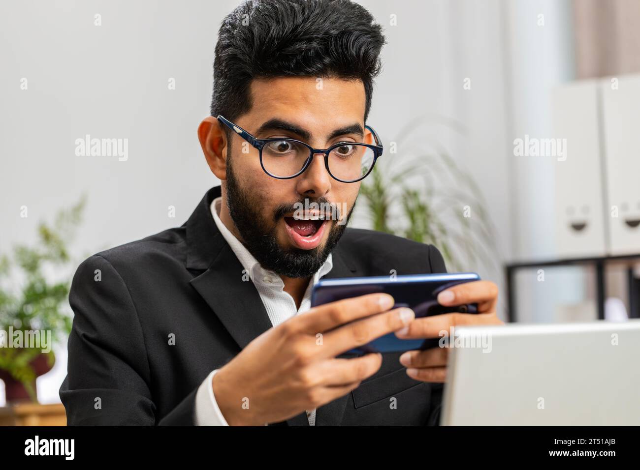 Excited Indian businessman playing on smartphone mobile application ...