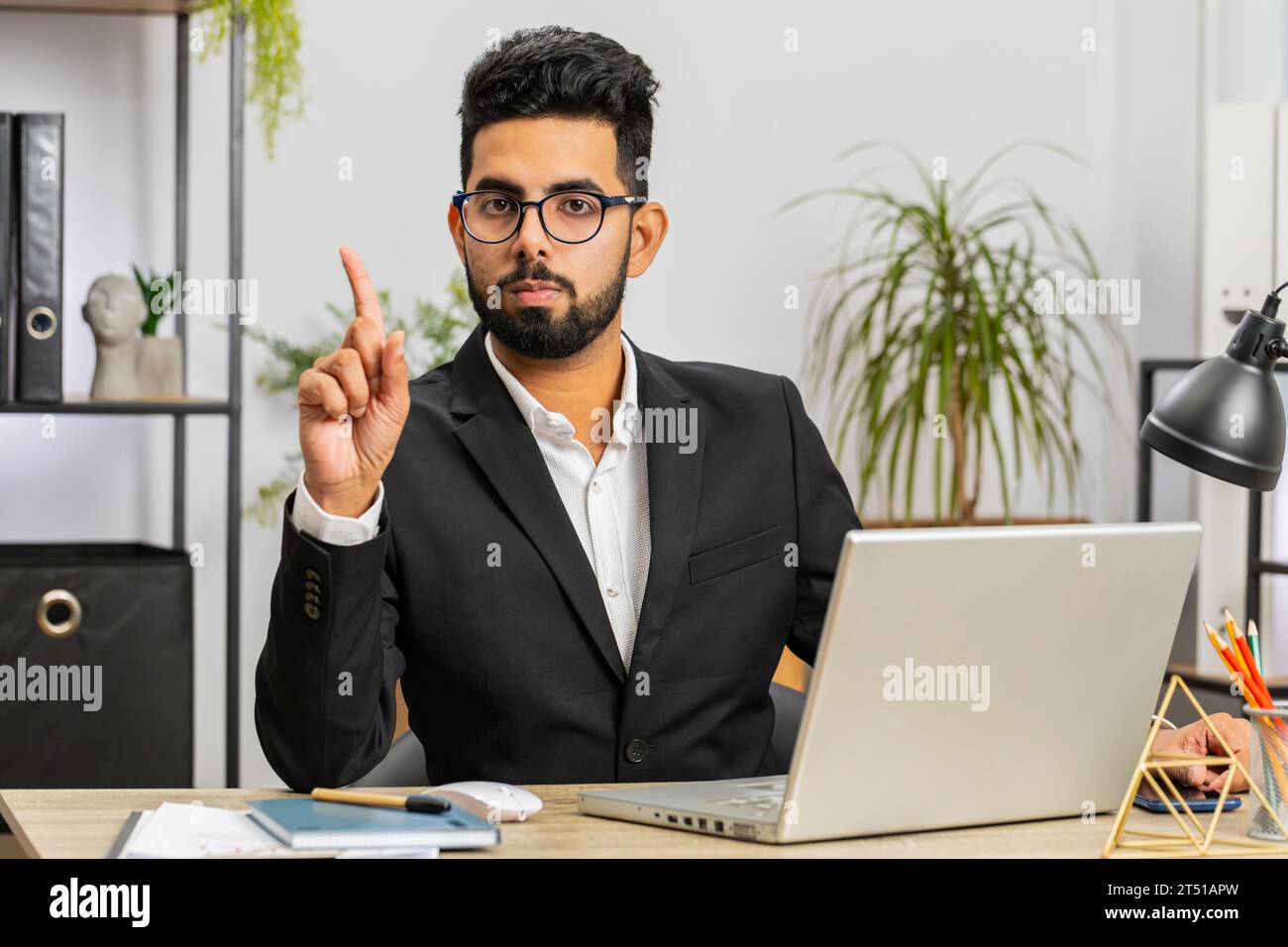 Indian young businessman working on laptop computer shakes finger and ...