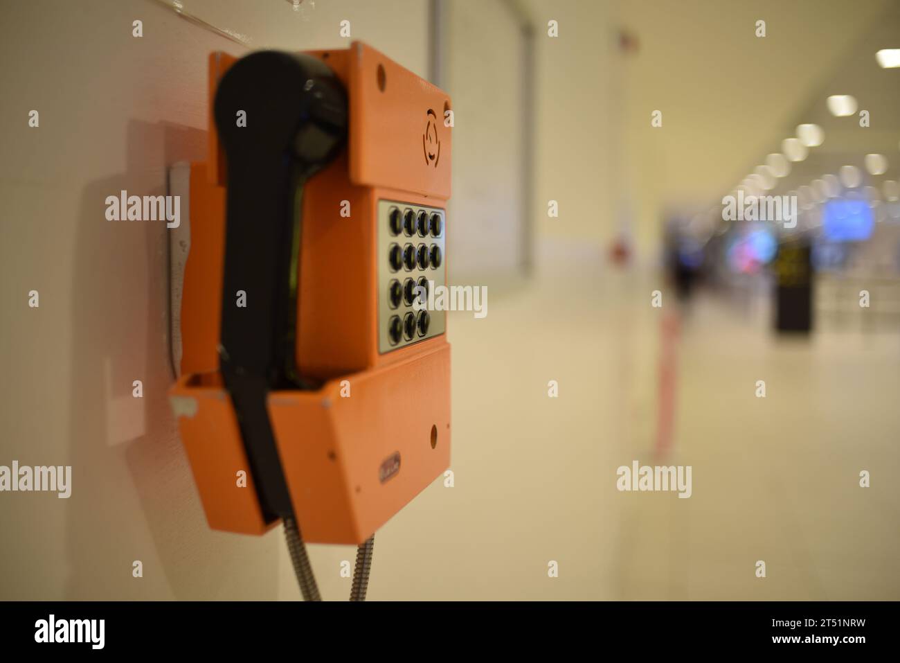 A traditional orange and black wall-mounted phone is affixed to a ...