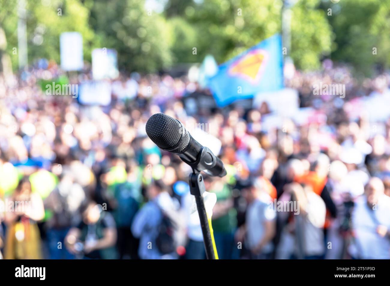Focus on microphone, blurred group of people at mass protest in the ...