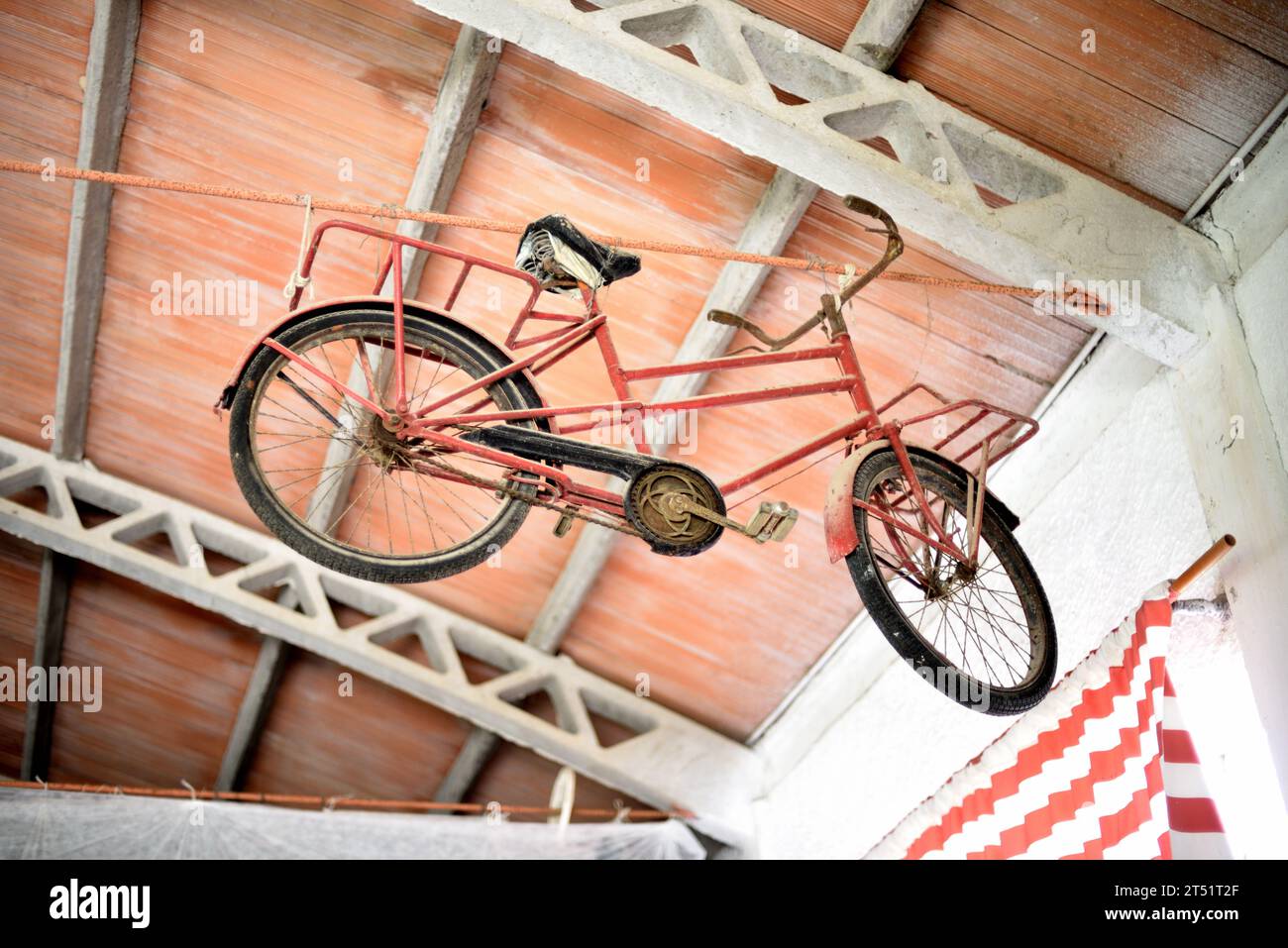 A rustic vintage bicycle is suspended from a wooden beam, resting in ...