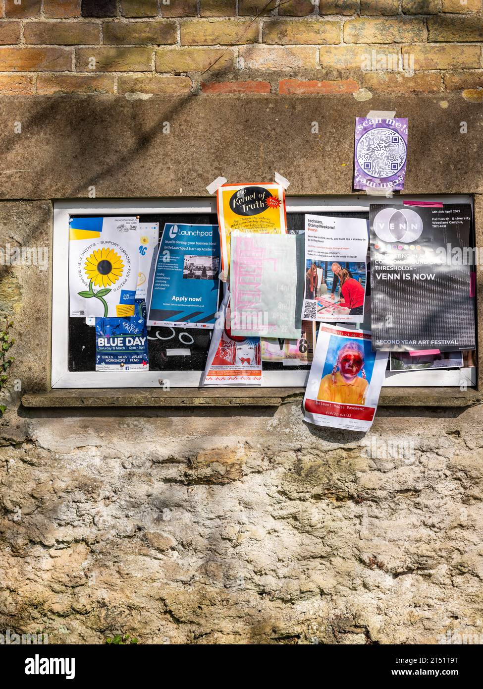 A noticeboard, uncovered on an outside wall, displaying pinned ...