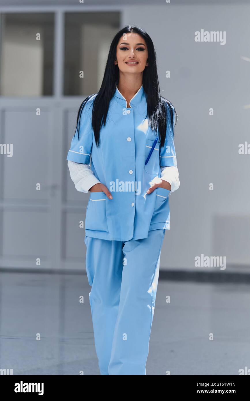 A modern black-haired female doctor stands confidently in the hallway ...