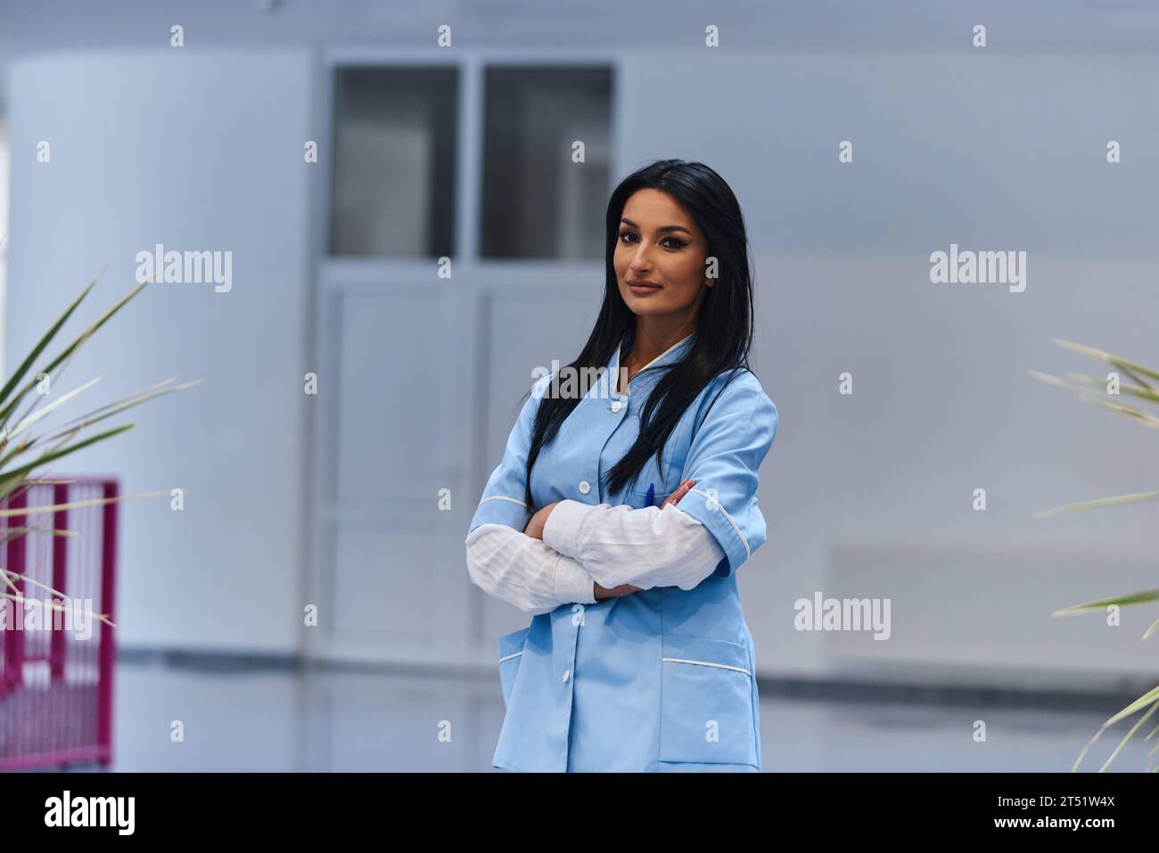 A modern black-haired female doctor stands confidently in the hallway ...