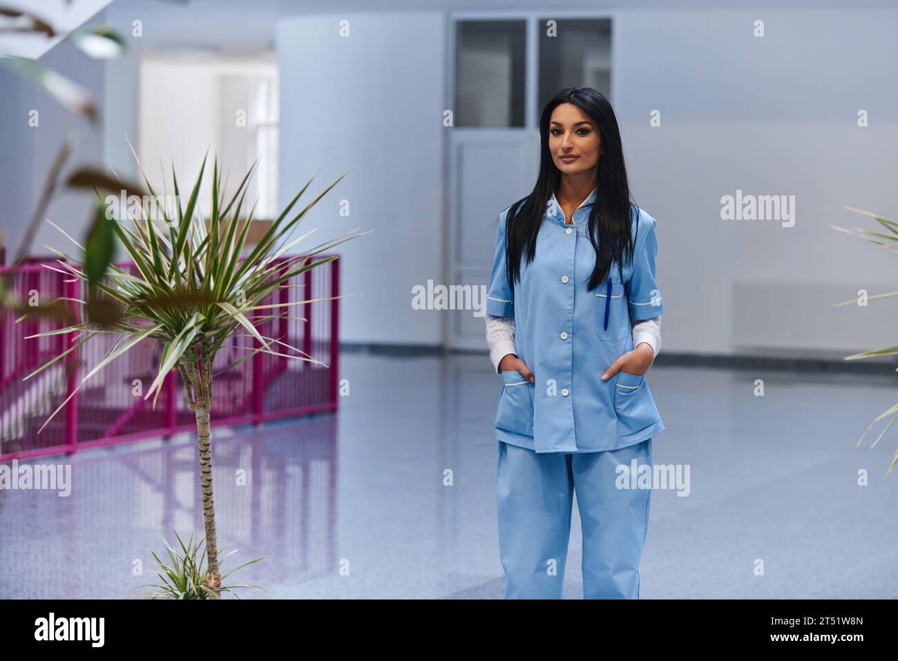 A modern black-haired female doctor stands confidently in the hallway ...