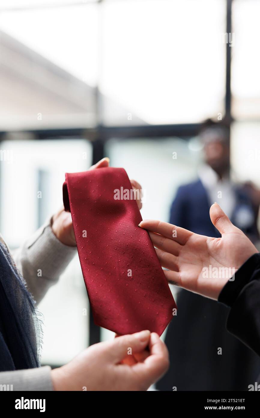 Elderly customer holding red tie analyzing material in clothing centre ...