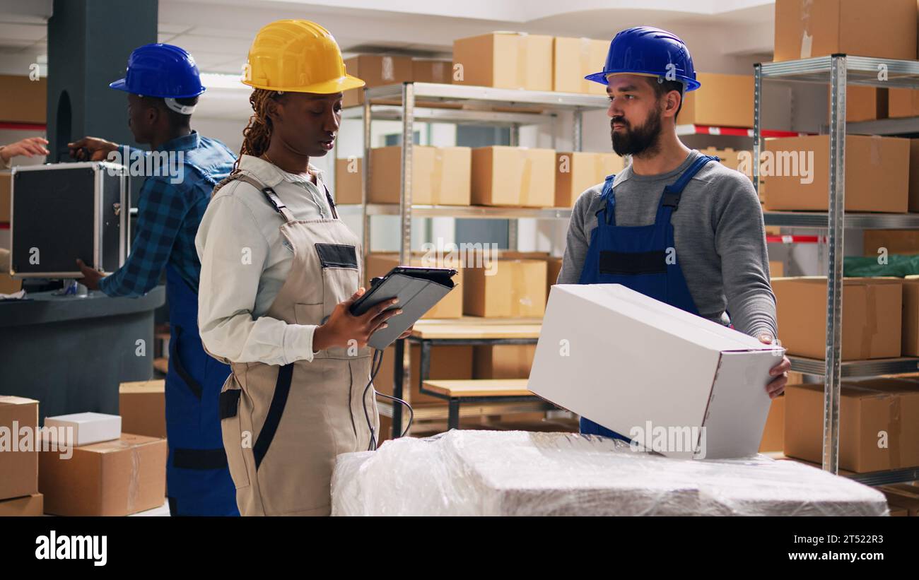 Diverse team of employees scanning boxes barcodes, looking at ...
