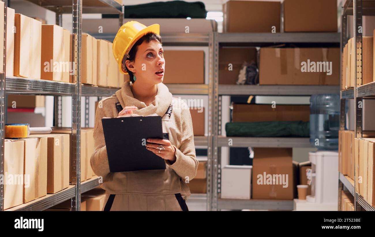 Young woman checking list of merchandise in depot, working on stock ...