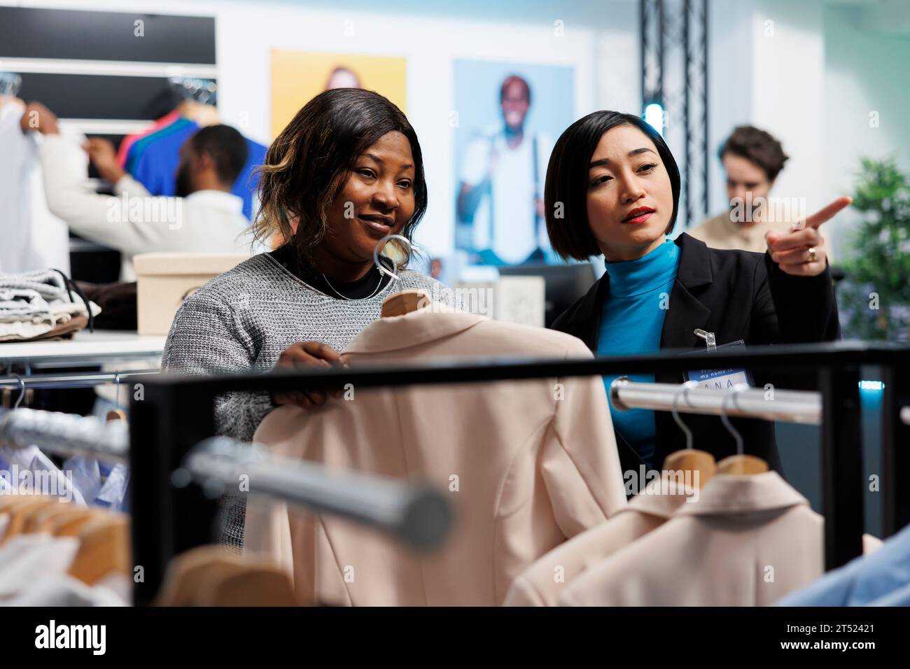 Clothing store asian employee pointing with finger and showcasing ...