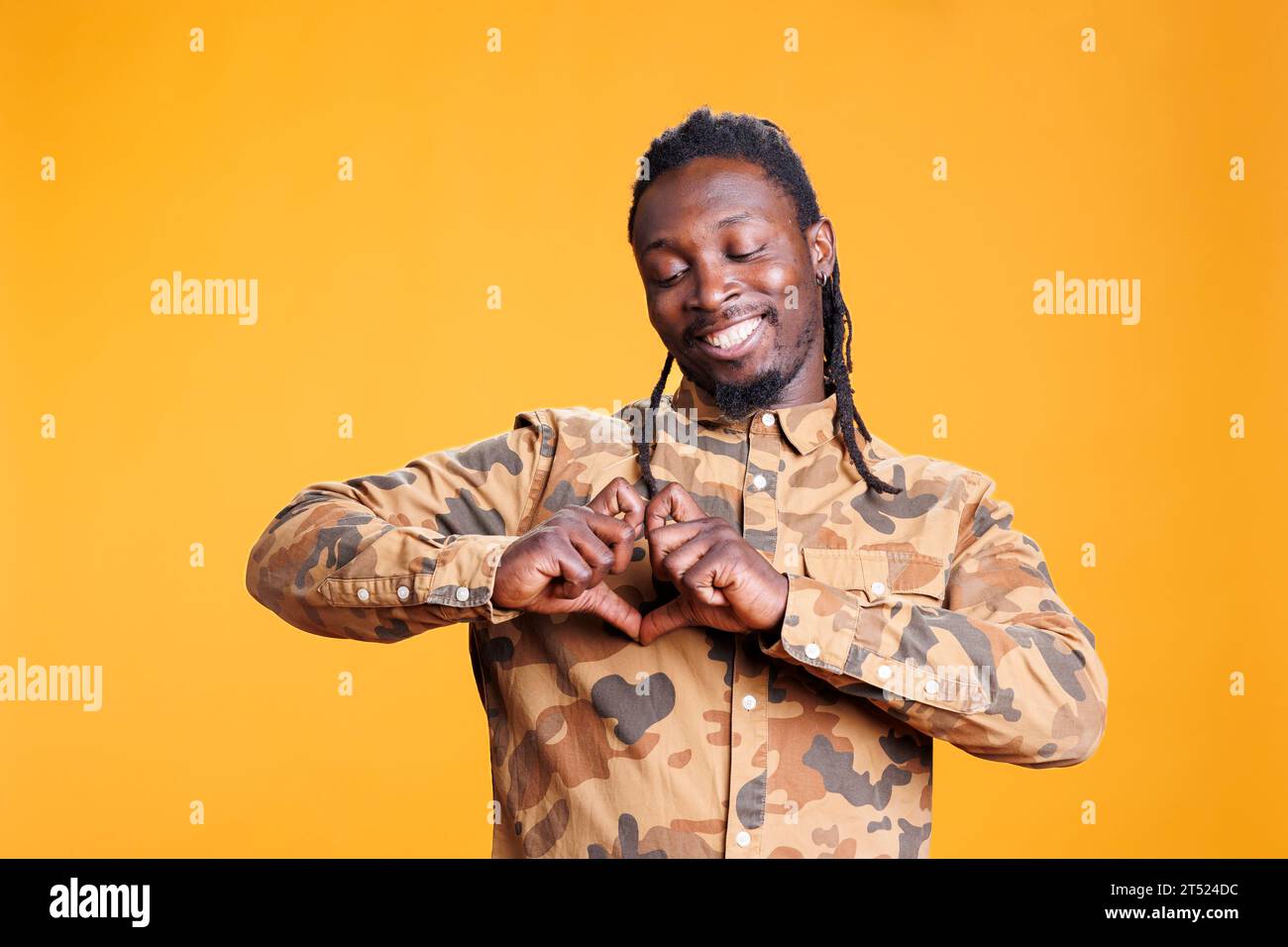 Smiling adult doing heart shape with hands on camera, promoting love in ...