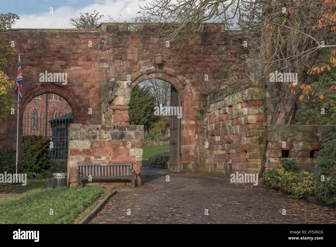 Gateway with two arches leading into a garden with a garden bench a ...