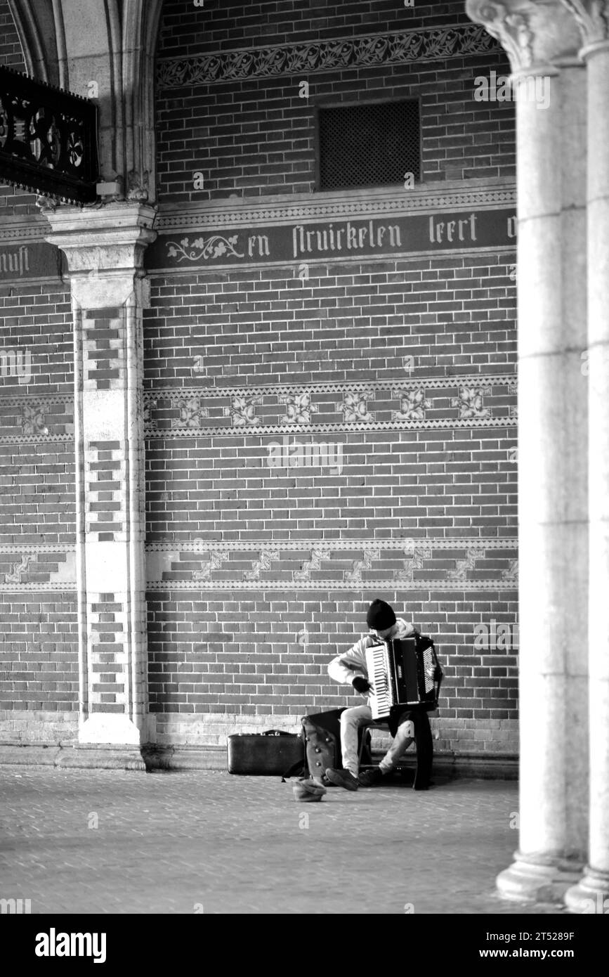 An adult male is seated atop a wooden bench in a well-lit outdoor ...