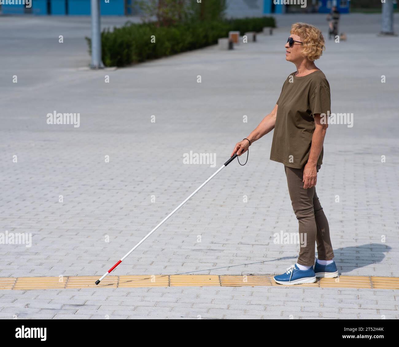 Close-up of the legs of an elderly blind woman with a cane at a tactile ...