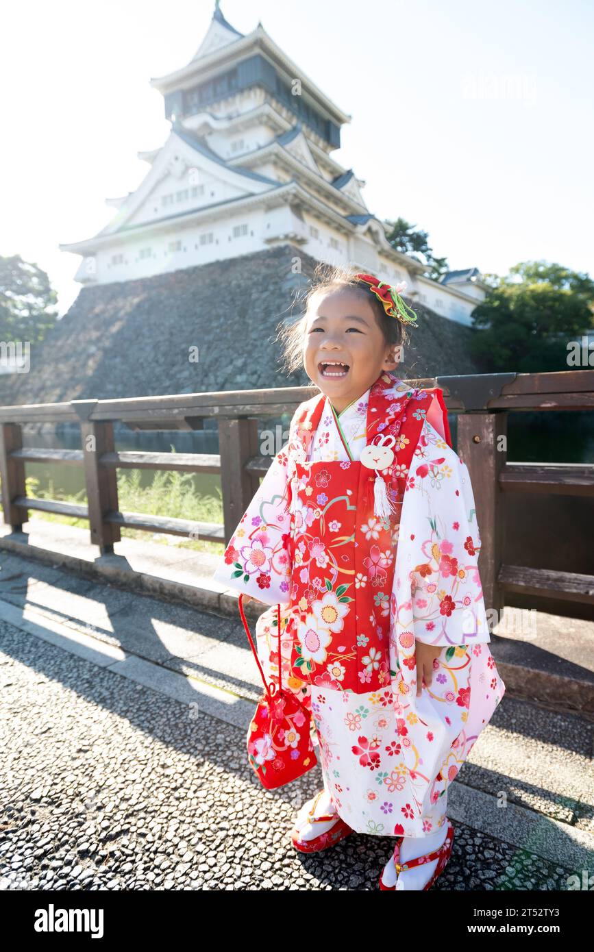 A happy little toddler girl wearing a kimono at a Japanese castle Stock ...