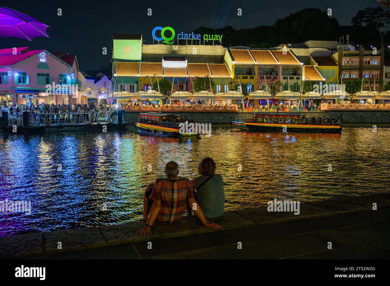 A Couple sitting by the river watching the River cruise boats at Clarke ...
