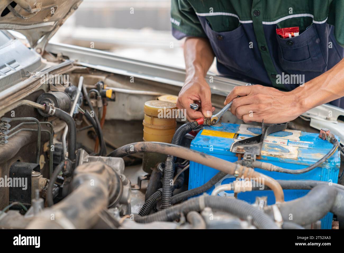 A mechanic tightens the battery terminals with a wrench after charge ...