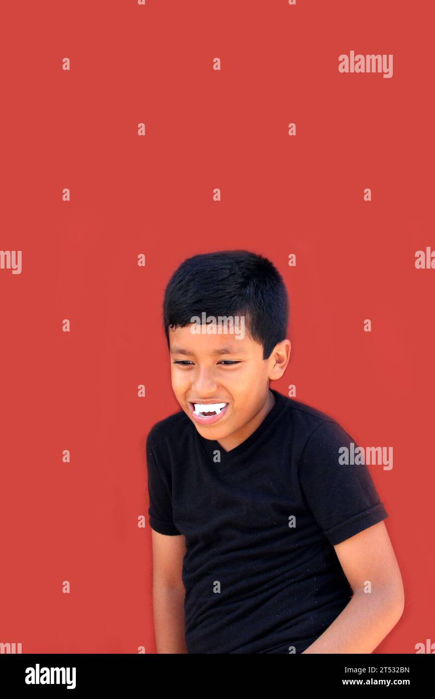 9-year-old dark-skinned Latino boy plays with his vampire costume fangs ...
