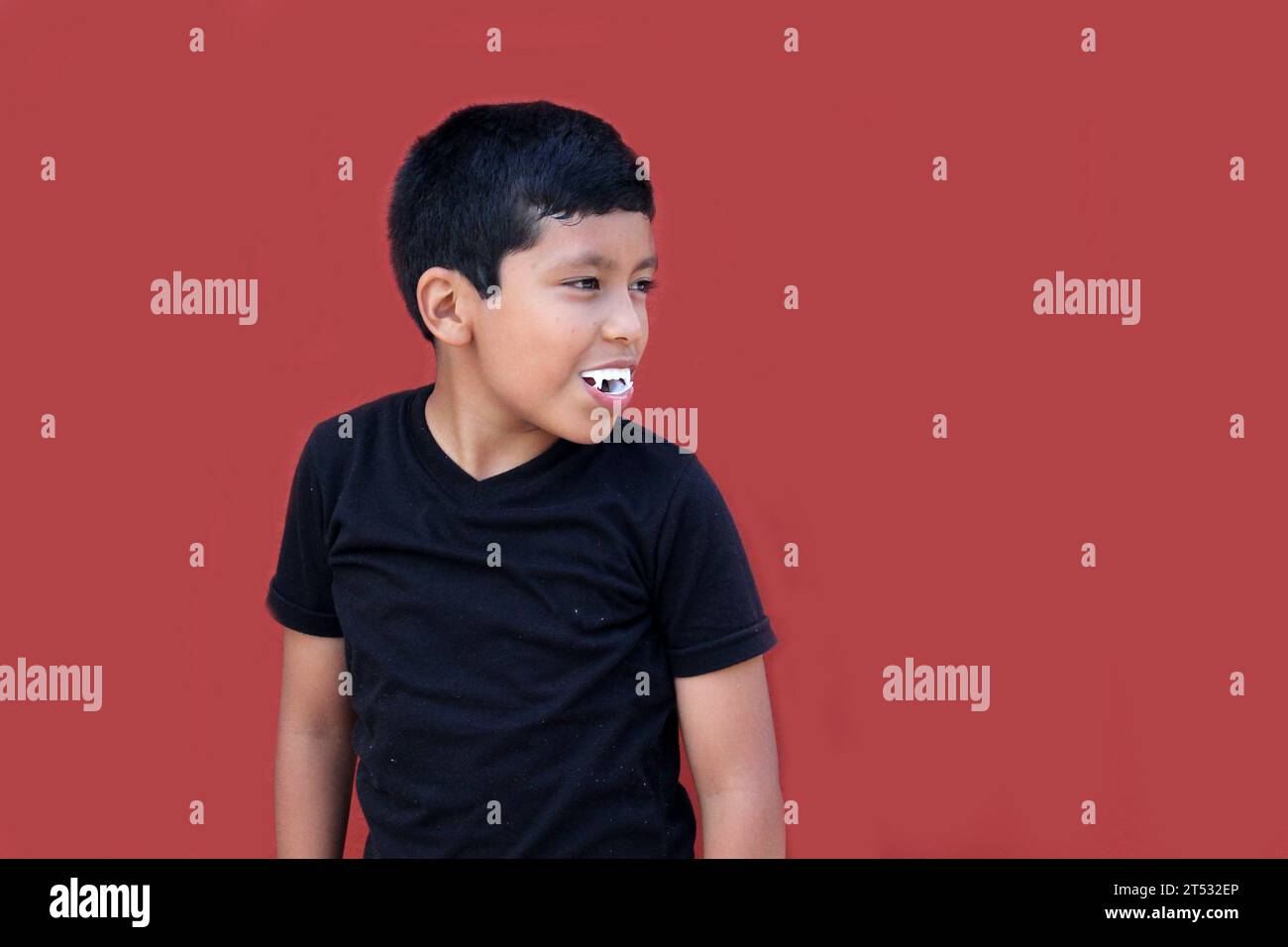 9-year-old dark-skinned Latino boy plays with his vampire costume fangs ...