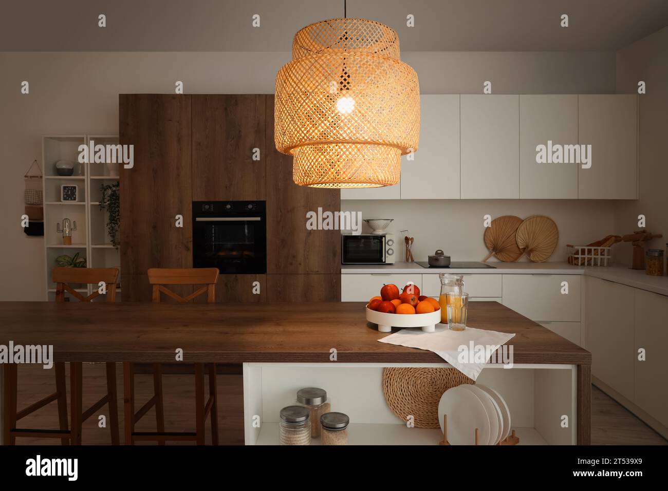 Interior of modern kitchen with wooden island table and glowing lamp ...