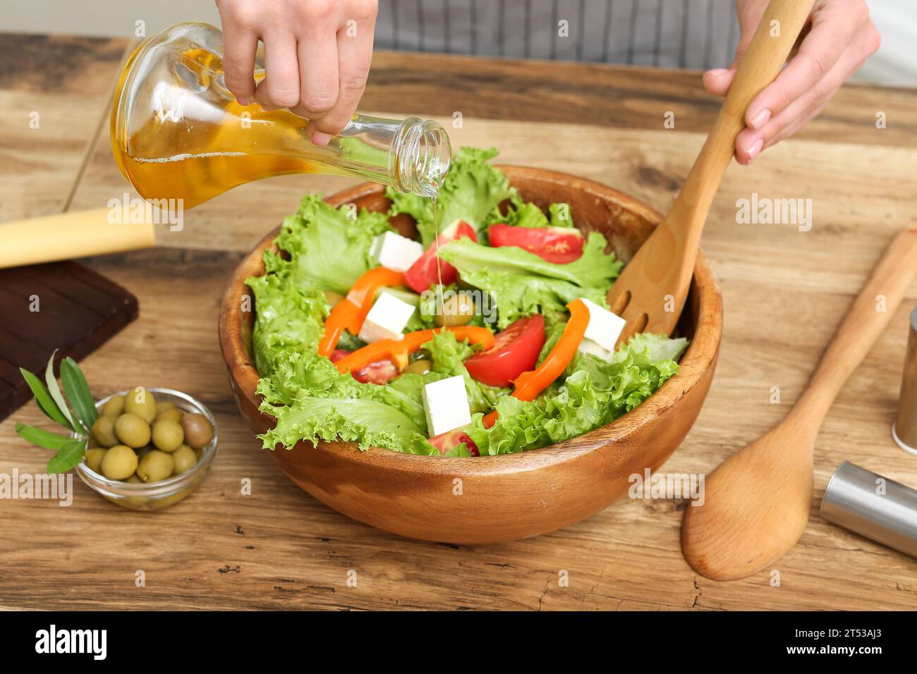 Woman adding olive oil into bowl with tasty salad at table Stock Photo ...