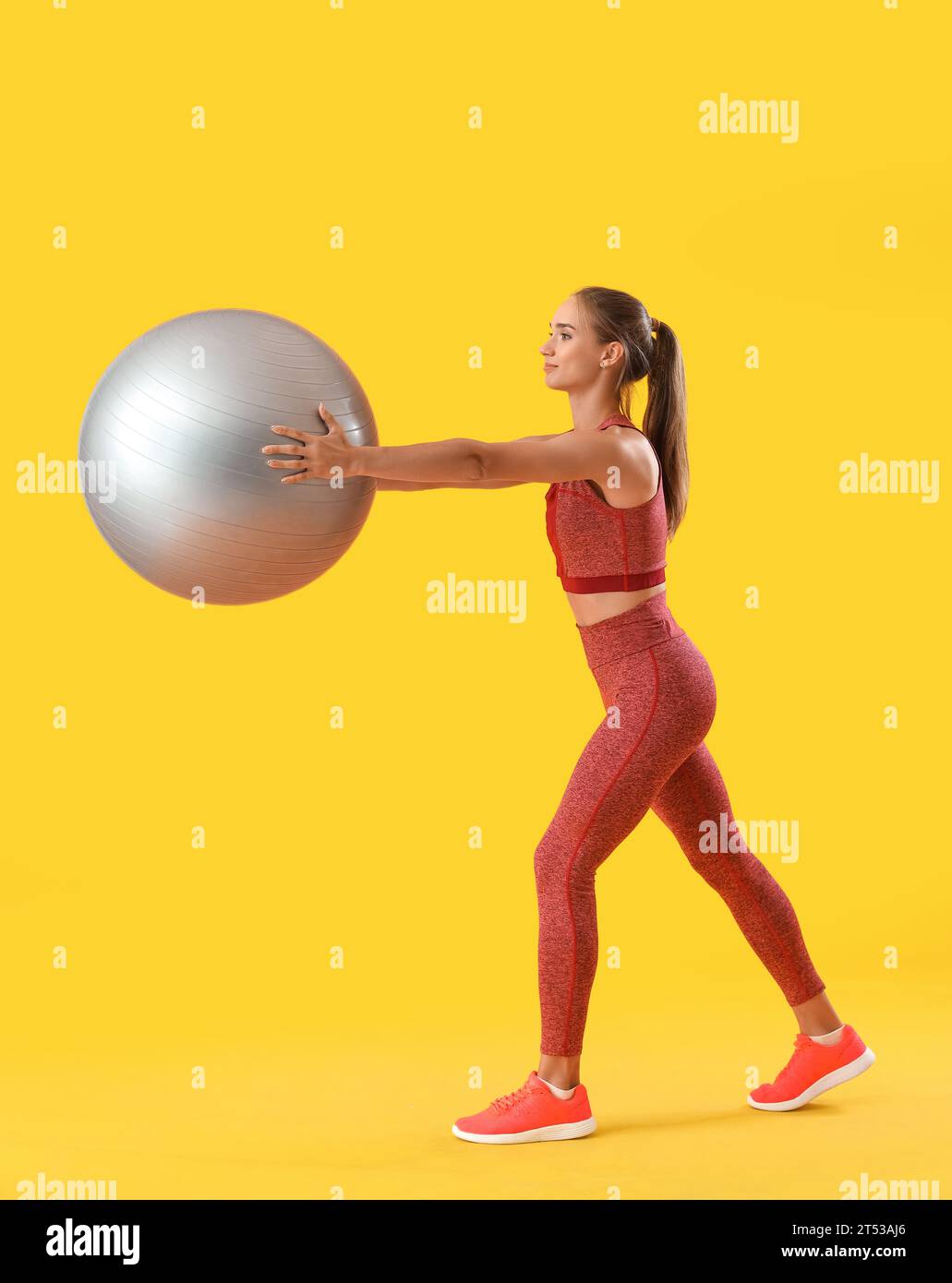Sporty young woman training with fitball on yellow background Stock ...
