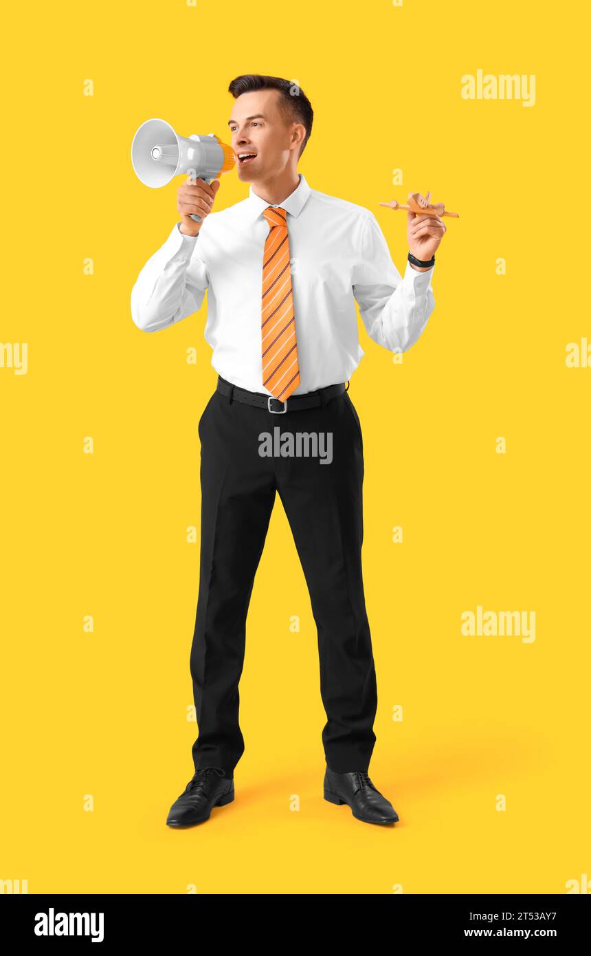 Handsome steward with wooden airplane shouting into megaphone on yellow ...