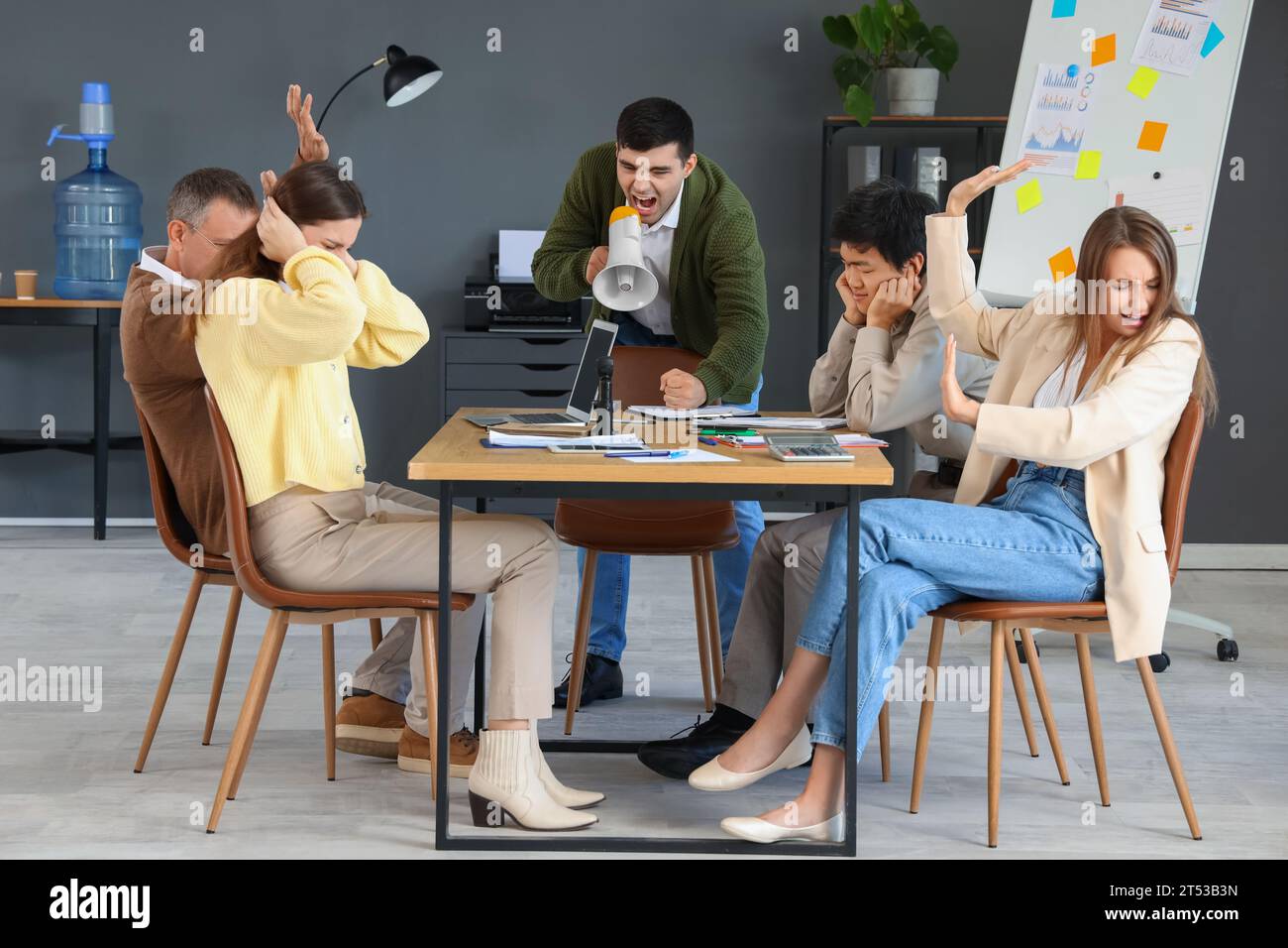 Angry young businessman with megaphone shouting at colleagues in office ...