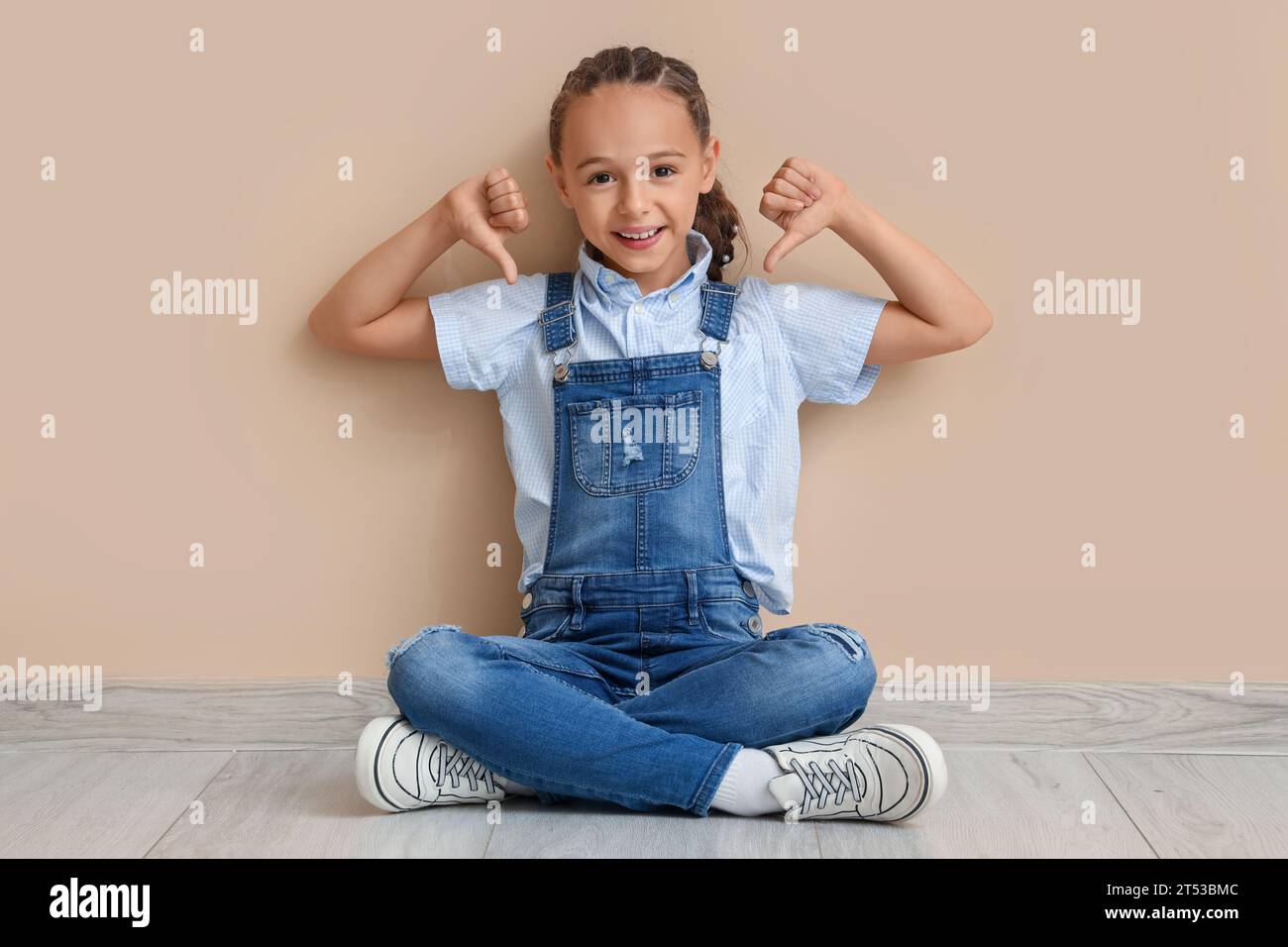 Little girl showing dislike near beige wall Stock Photo - Alamy
