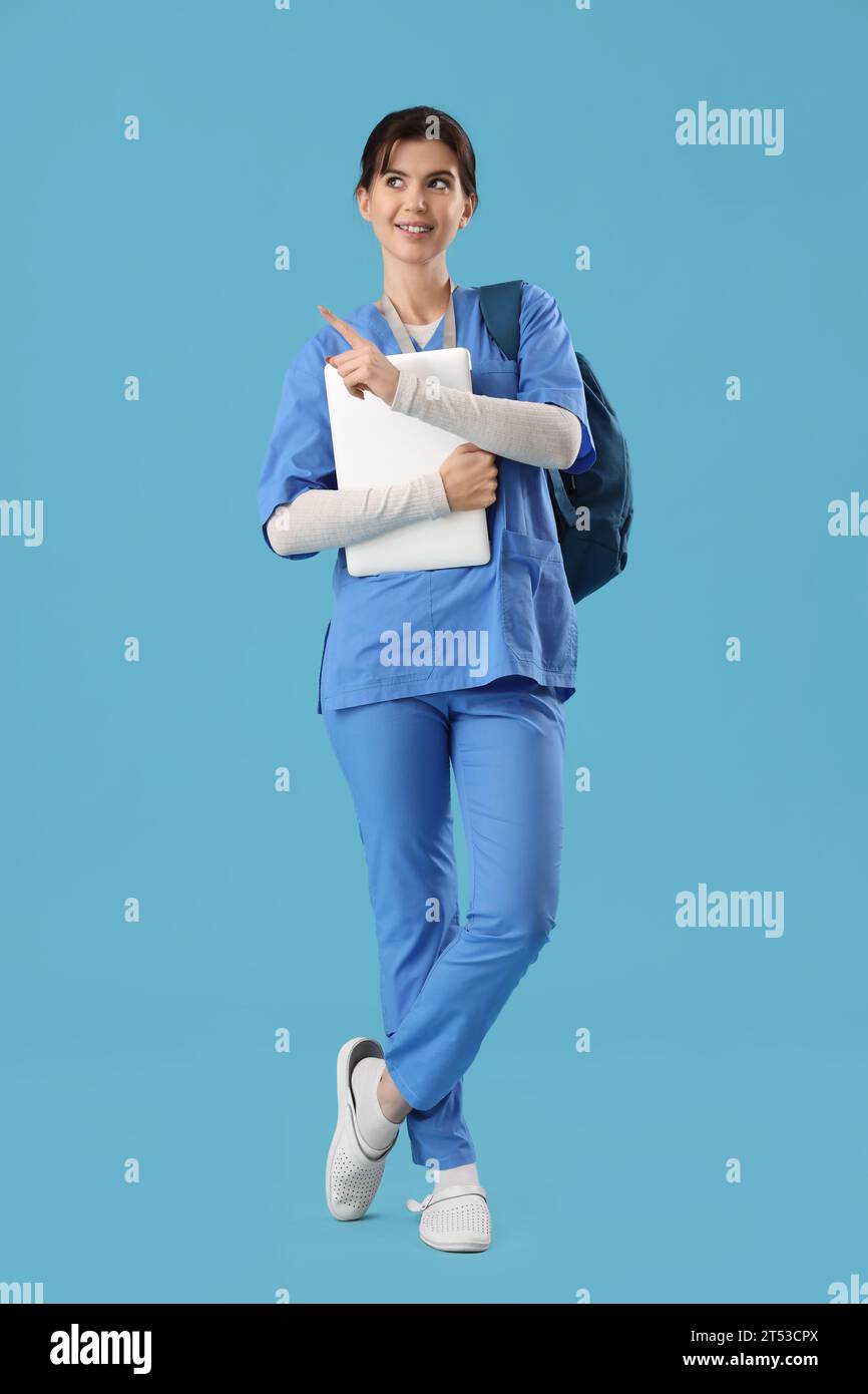 Female medical intern with laptop pointing at something on blue ...
