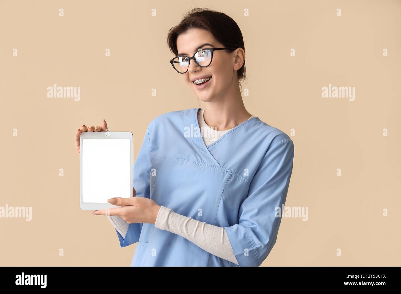 Female medical intern with tablet computer on beige background Stock ...