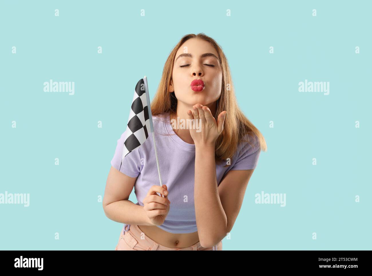 Beautiful young woman with racing flag blowing kiss on blue background ...