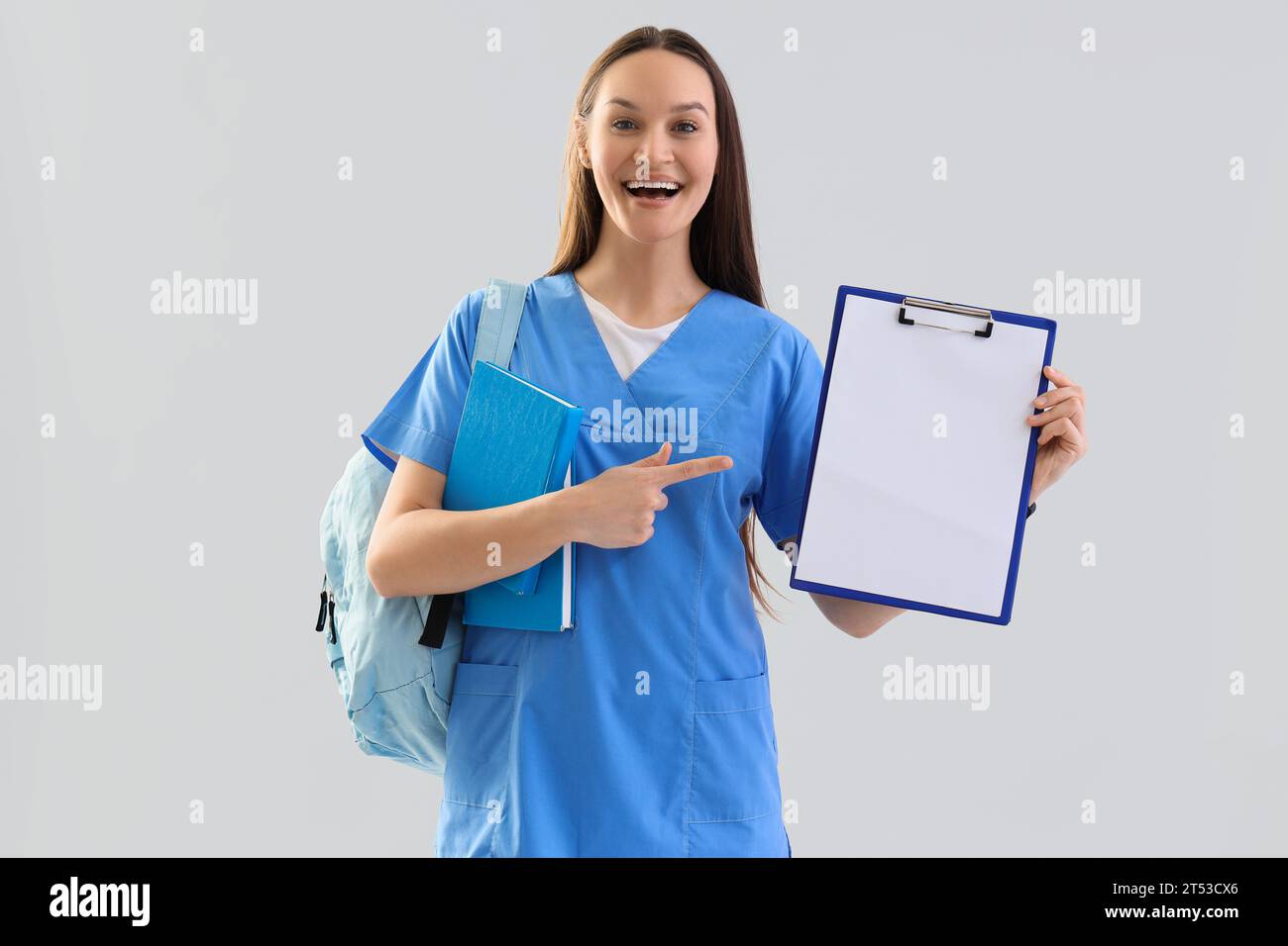 Female medical intern pointing at clipboard on light background Stock ...