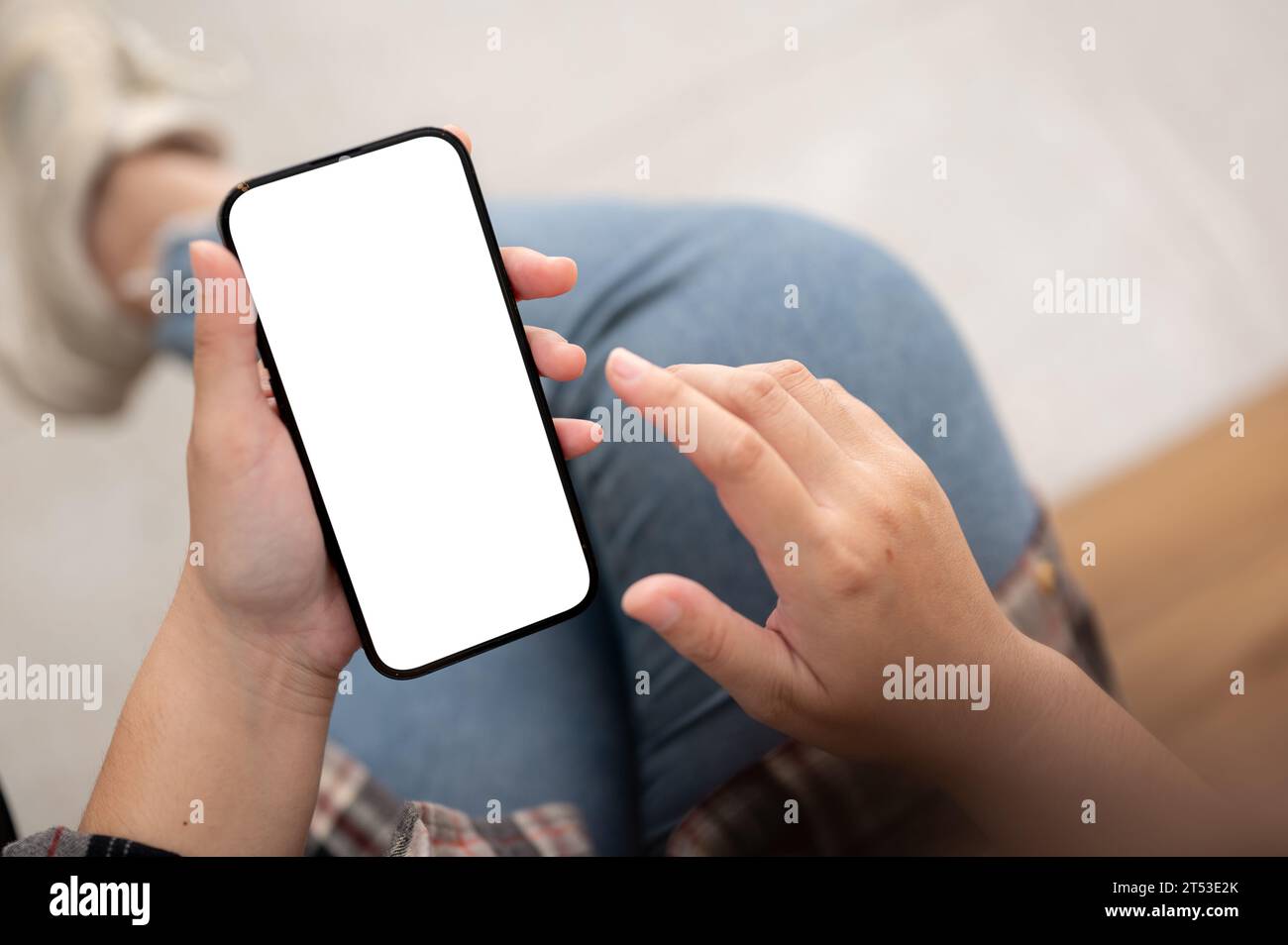 Top view image of a white-screen smartphone mockup in a woman's hand. A ...