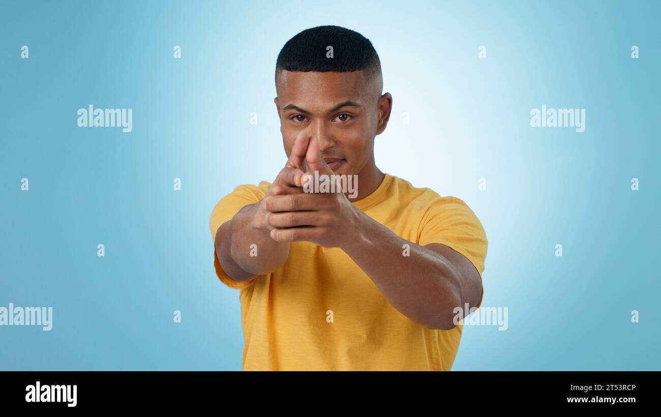 Portrait, finger gun and man aim at target in studio isolated on a blue ...