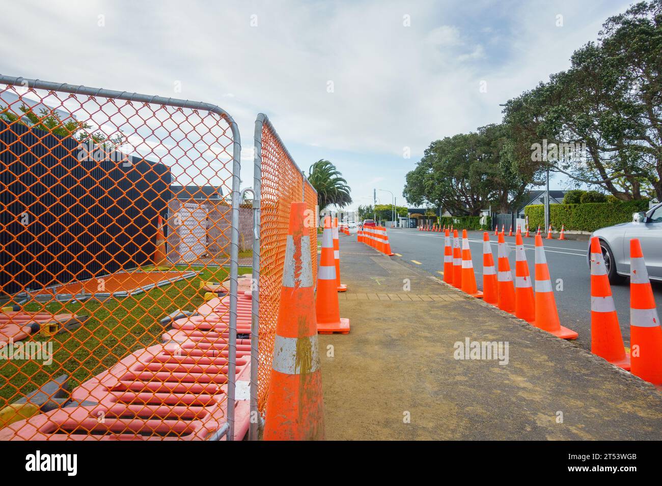 Orange traffic cones lining up the street. Cars driving on the road ...