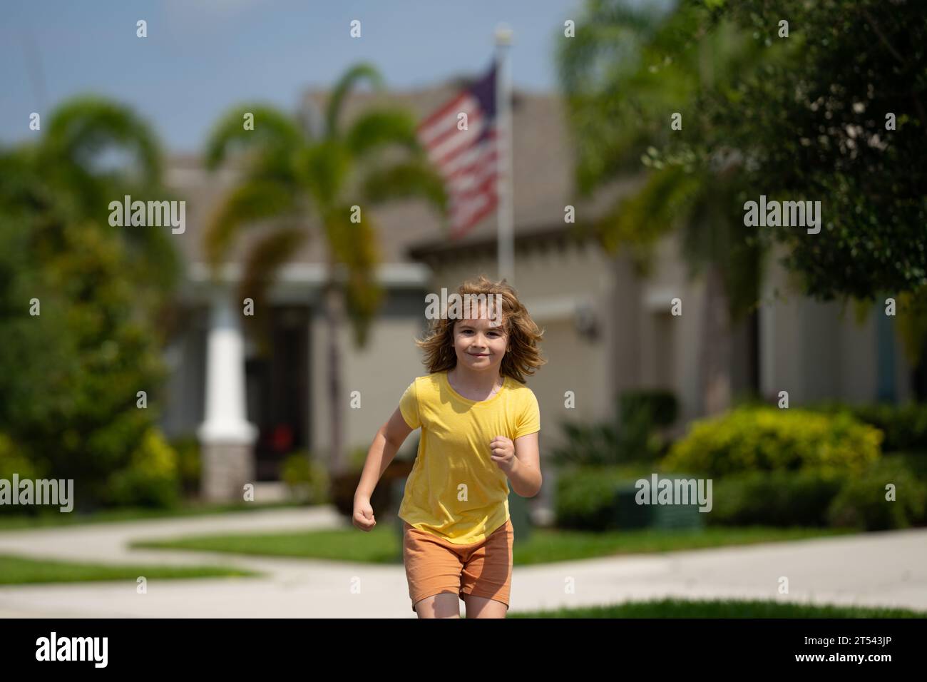 Cute kid boy running across american neighborhood street. Summer ...