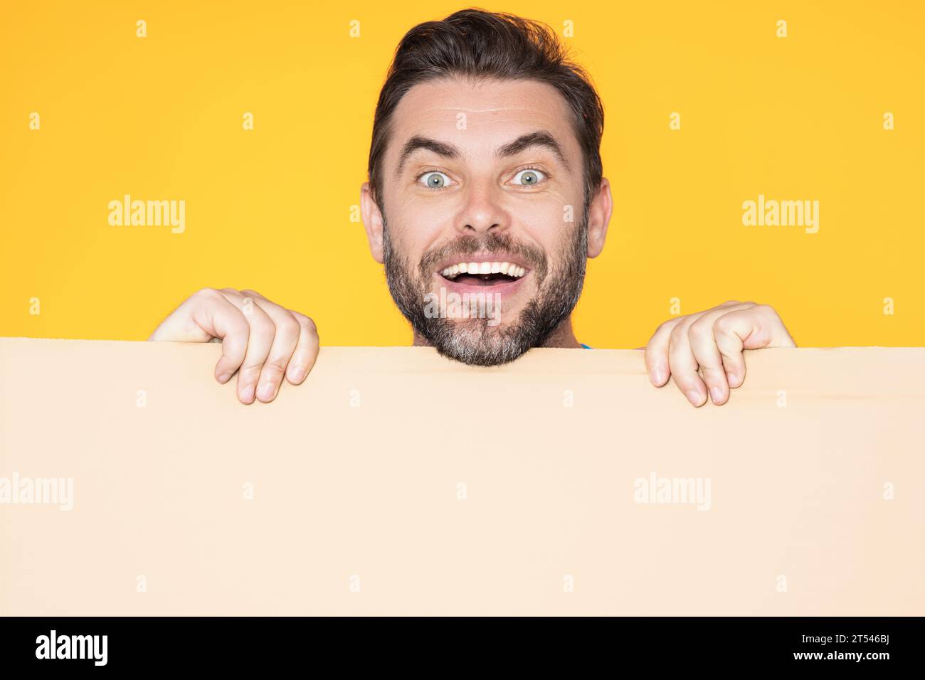 Happy guy with blank banner ad isolated on studio background. Portrait ...