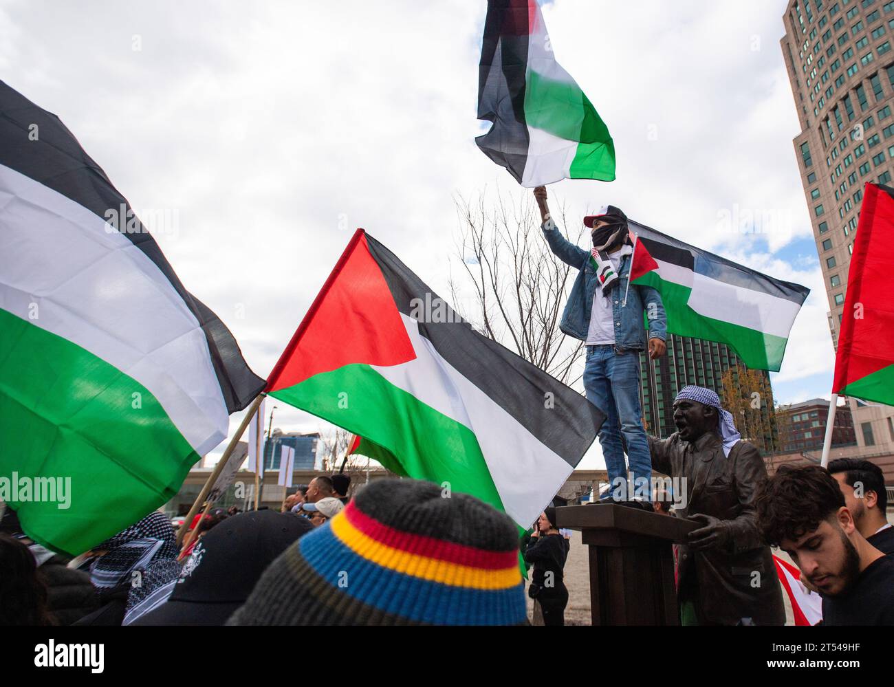 A protester waving a Palestinian Flag stands atop a statue of Martin ...