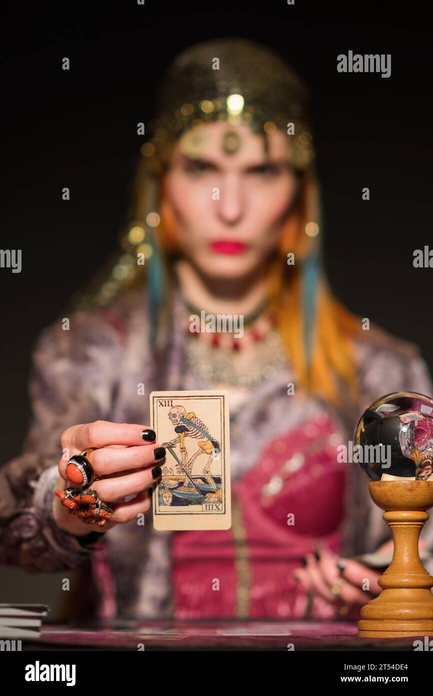 Blurred female fortune teller in makeup and stylish outfit looking at ...