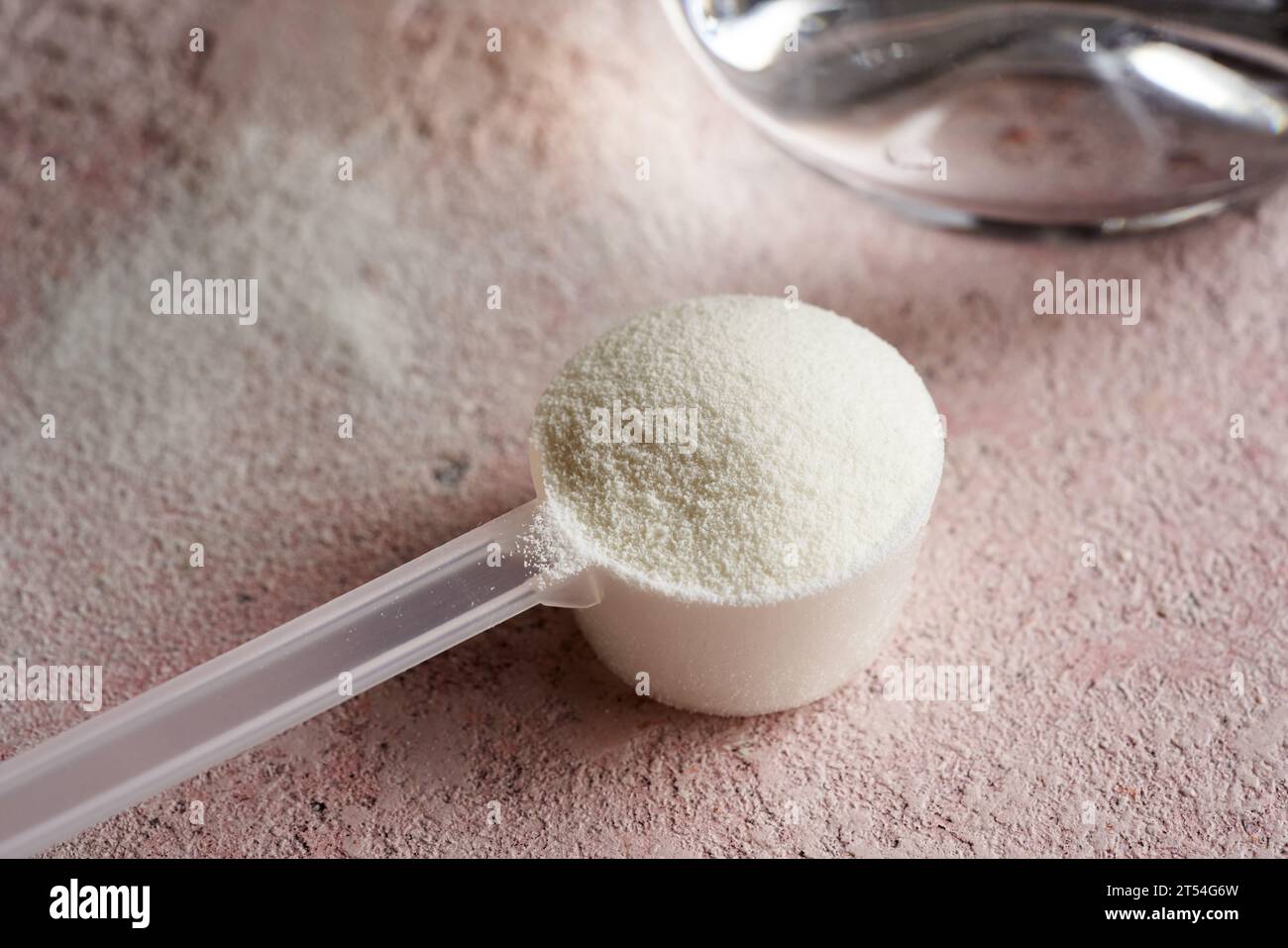 Collagen powder in a plastic measuring spoon on pink background Stock ...