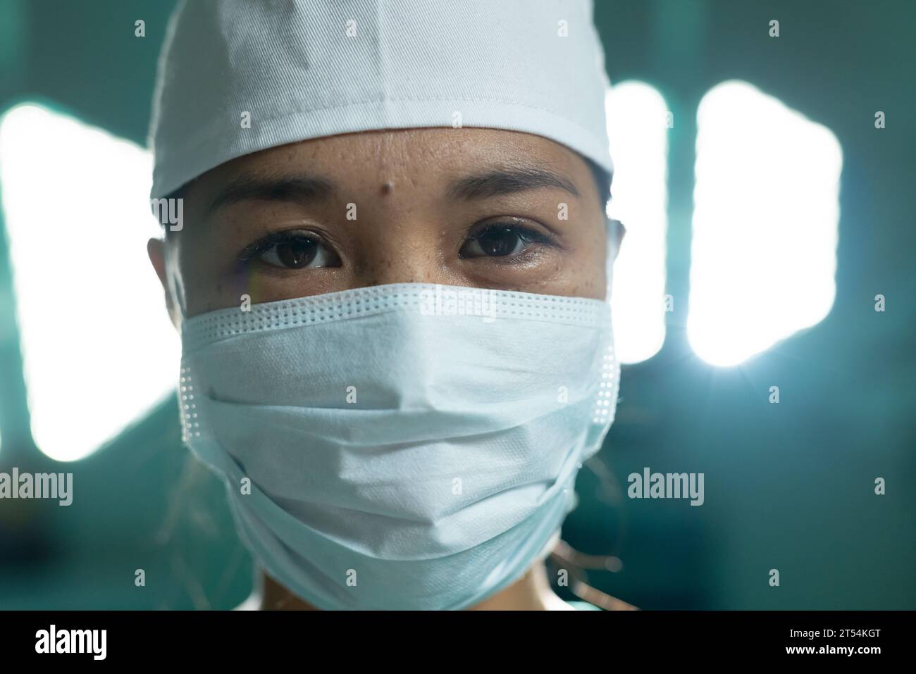 Portrait of asian female surgeon wearing face mask in operating theatre ...