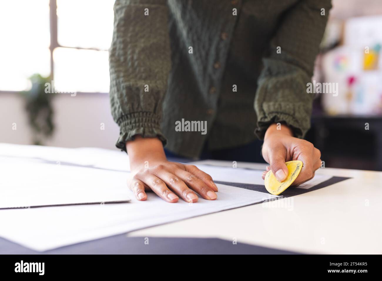 Hands of biracial female fashion designer using tailor's chalk in sunny ...