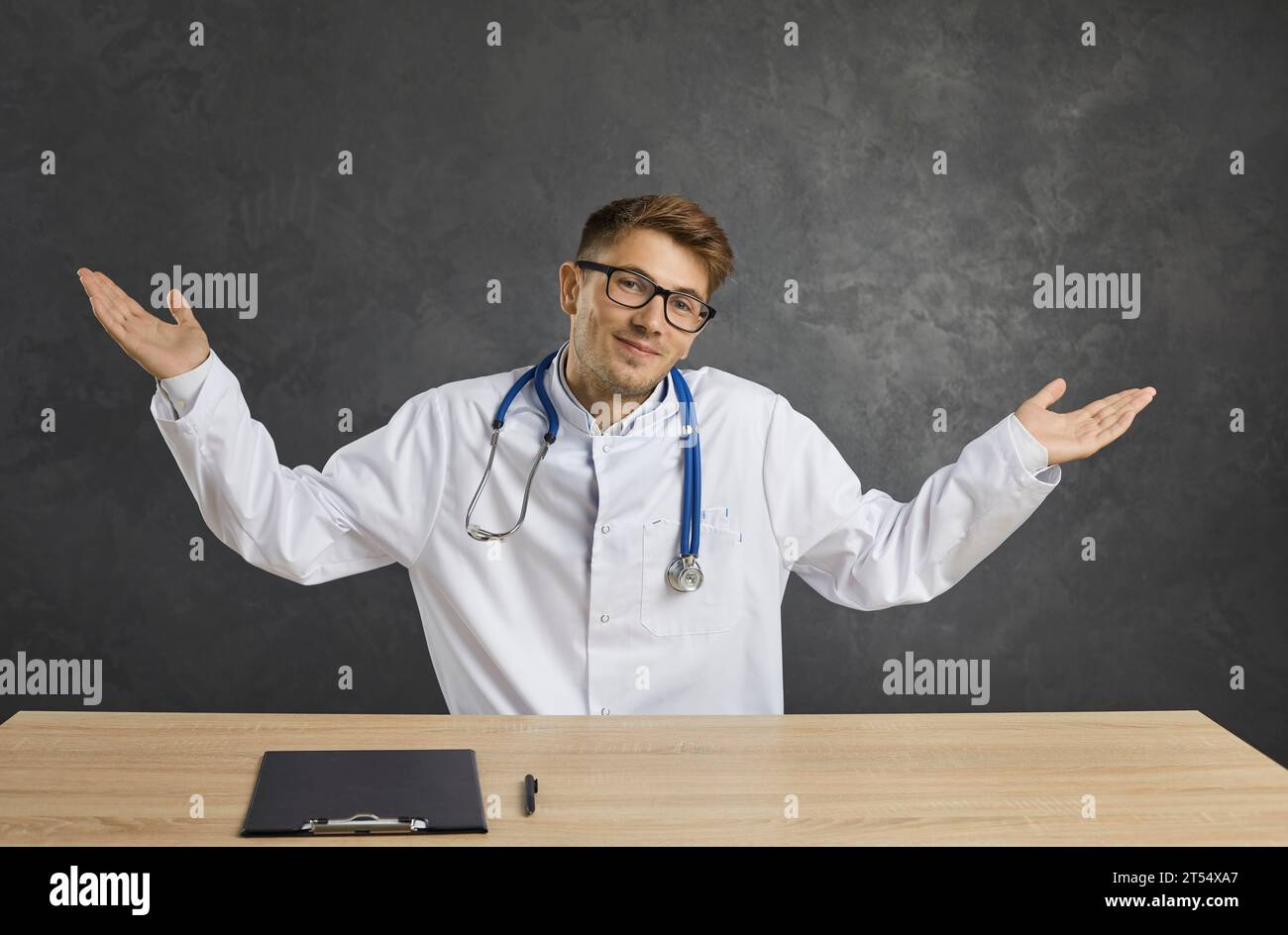 Portrait of a puzzled young doctor or nurse shrugging his shoulders in ...