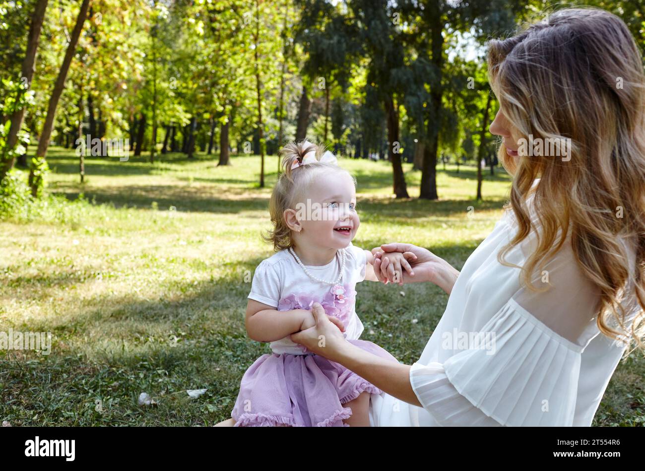 Mother and daughter walk in the summer city park. Childhood, leisure and people concept - happy ...
