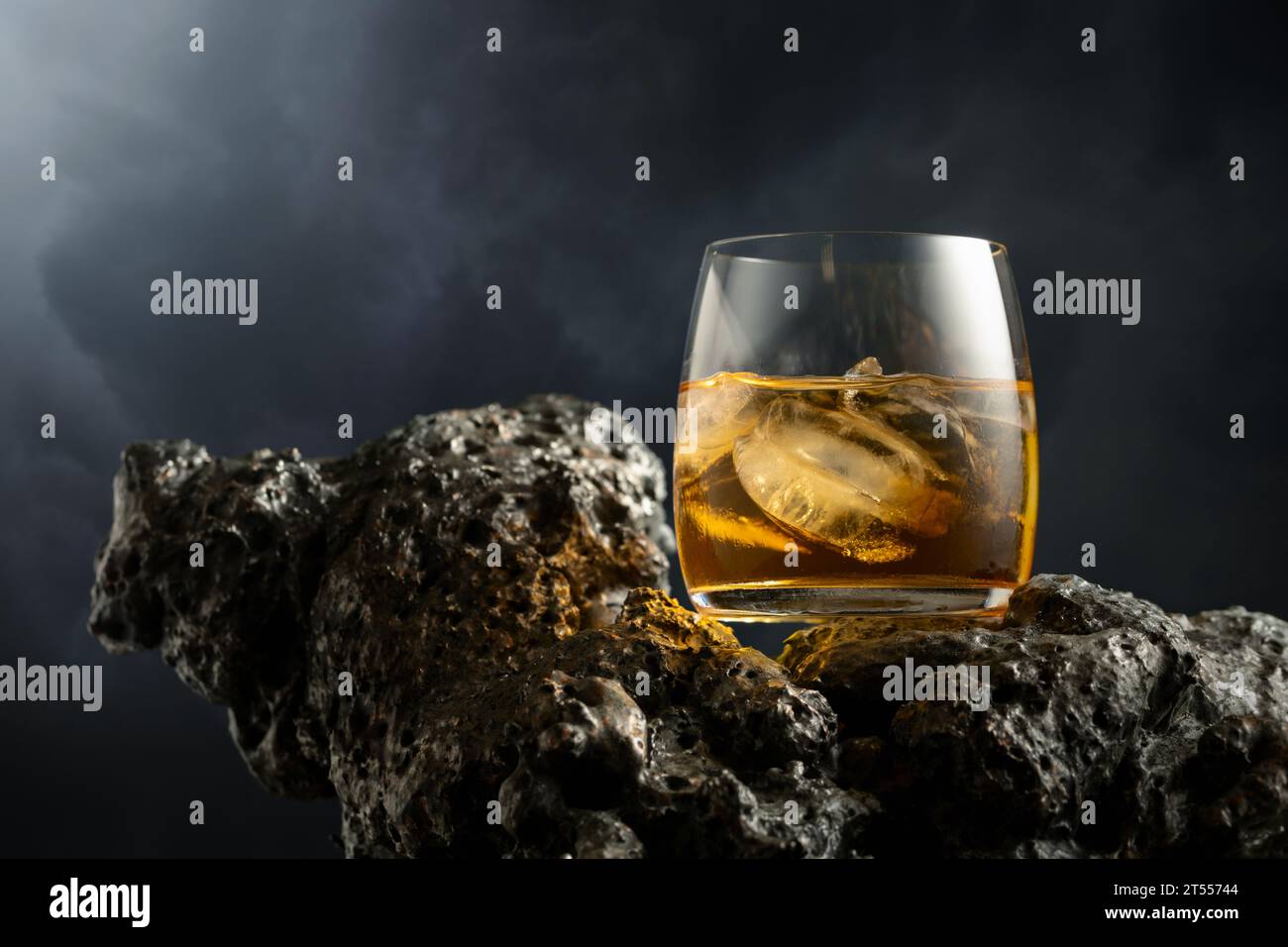 Whiskey with ice on a grey stone. Cold drink on a background of cloudy ...