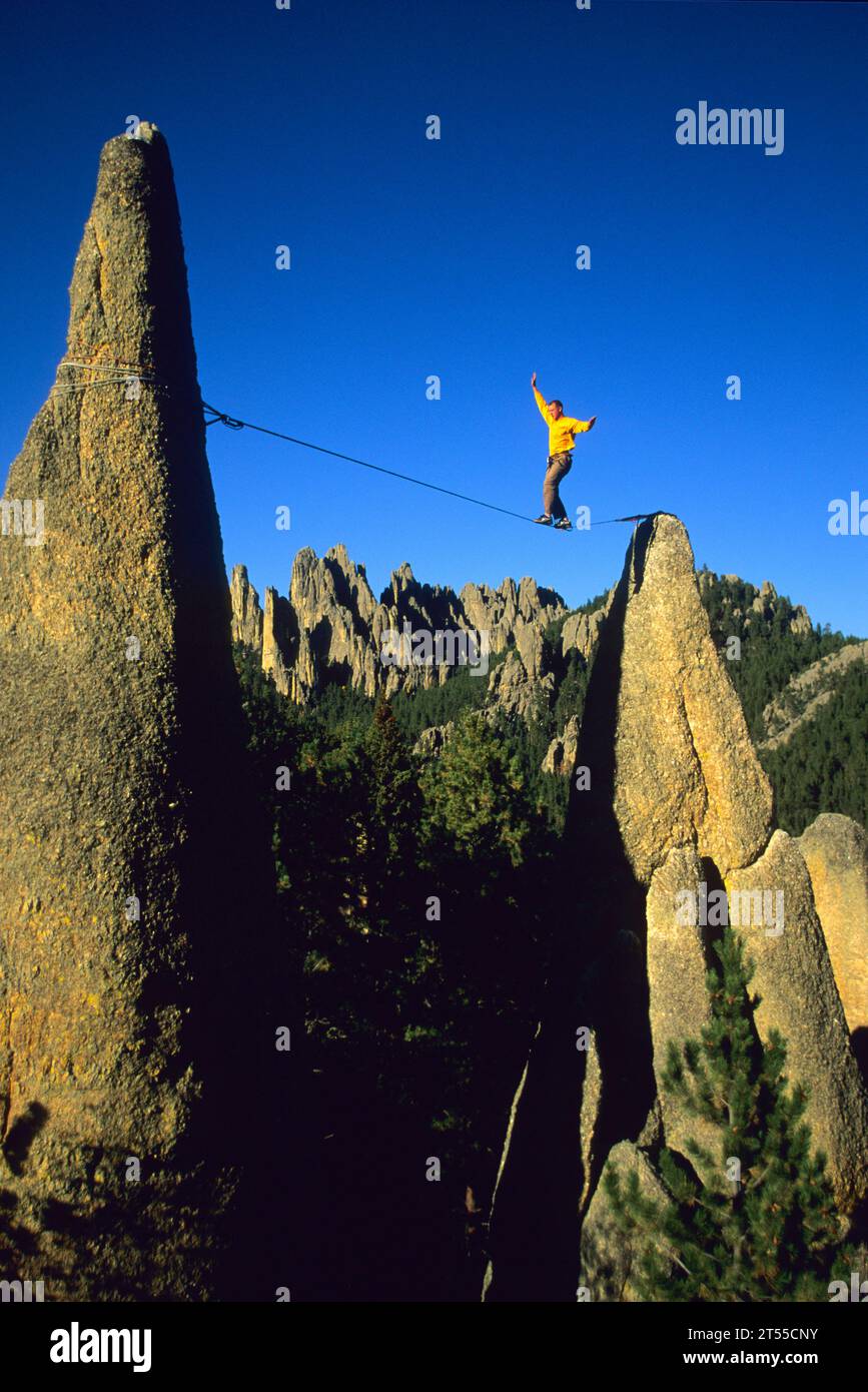 Male climber walking a tightrope between two granite spires, South ...